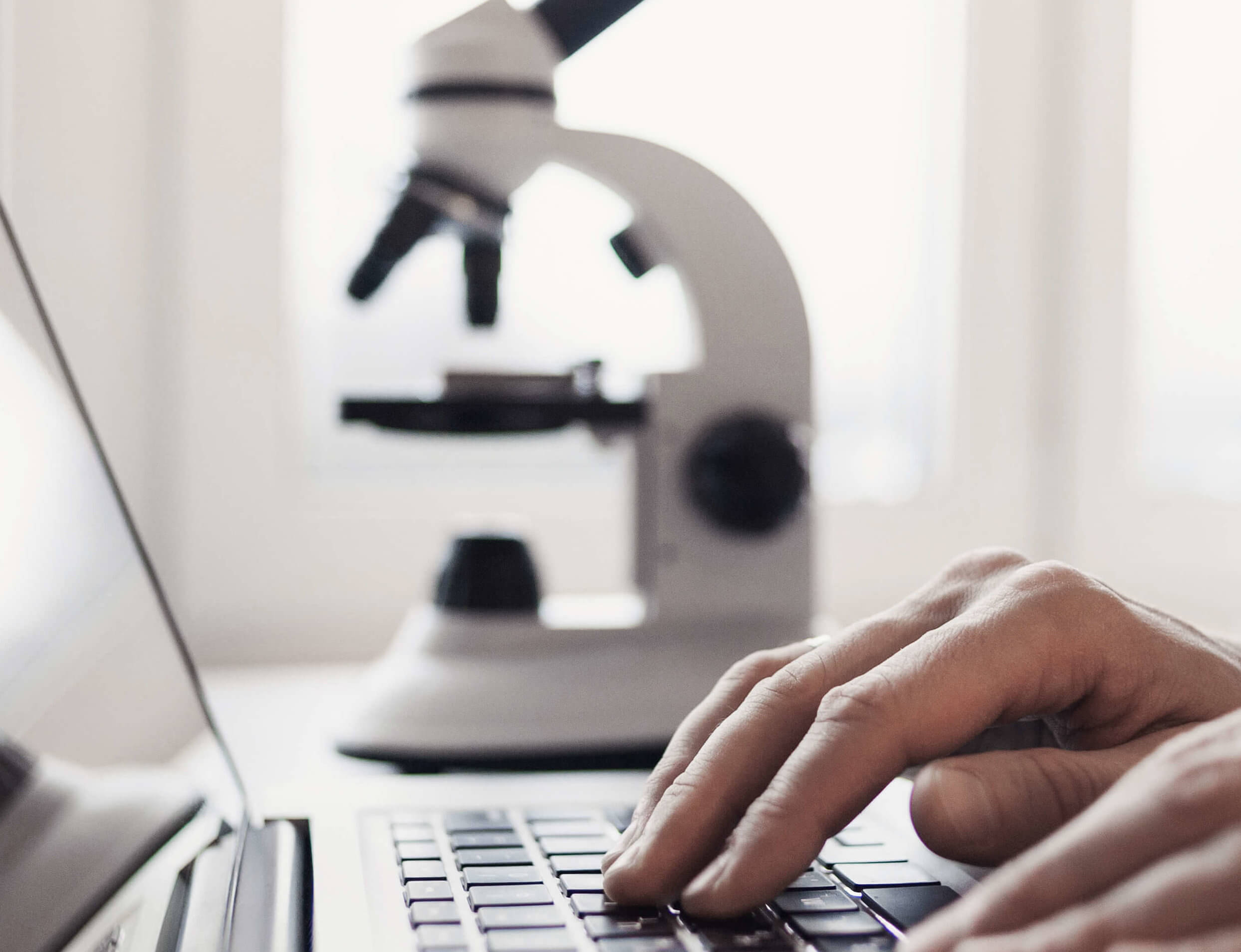 Scientist or student using laptop computer and microscope ...